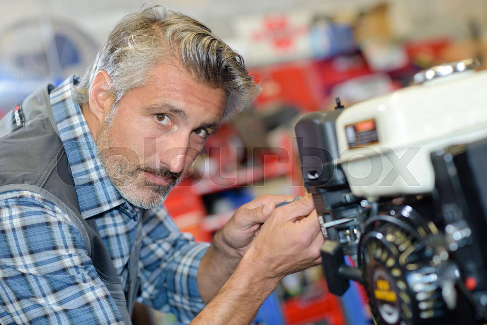 mechanic repairing lawnmower engine in garage | Stock image | Colourbox