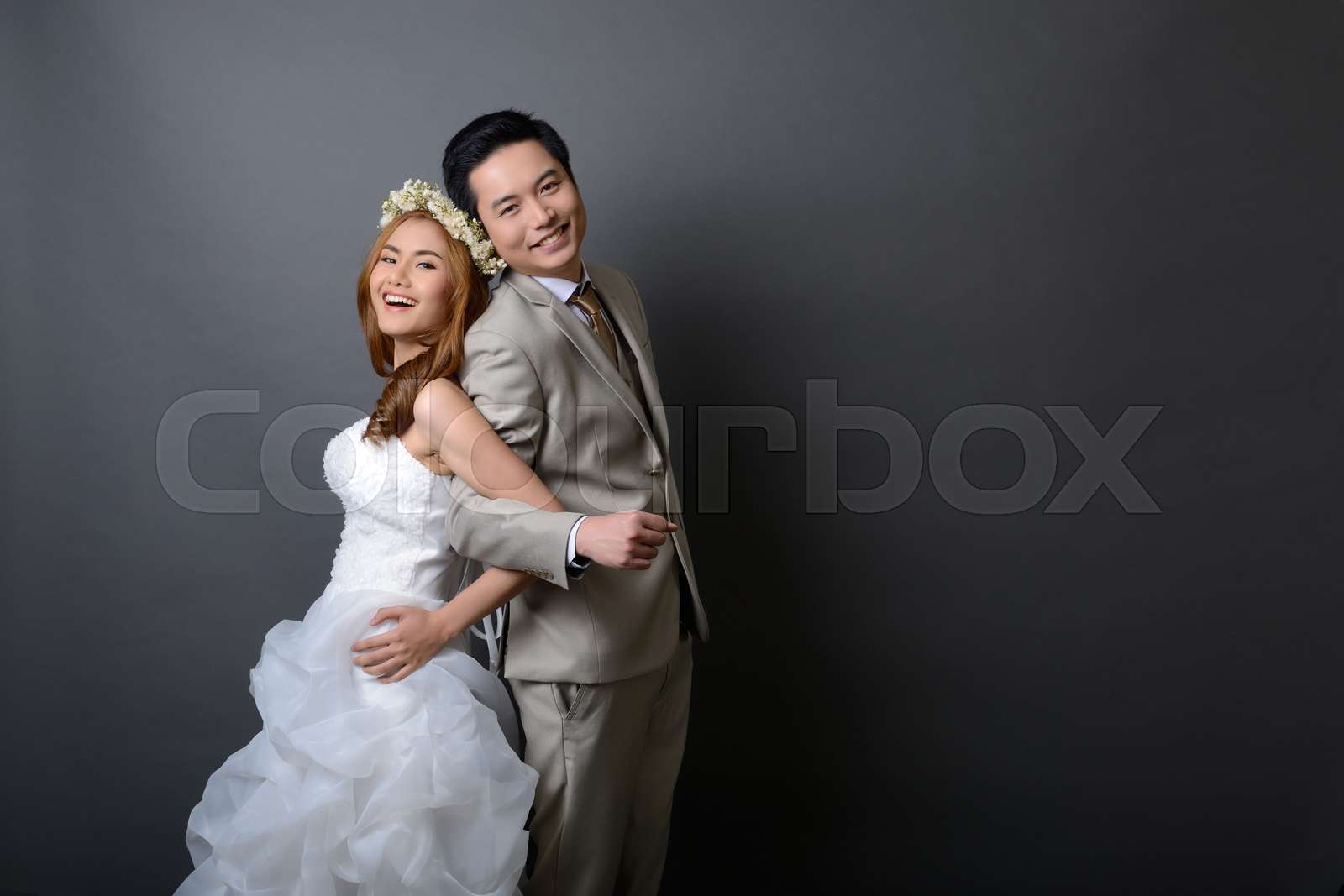 young asian groom and bride posing and smiling in studio for pre ...