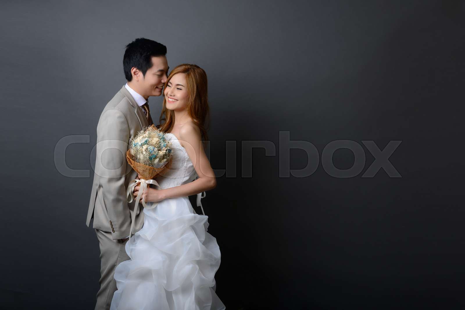 young asian groom and bride posing and smiling in studio for pre ...