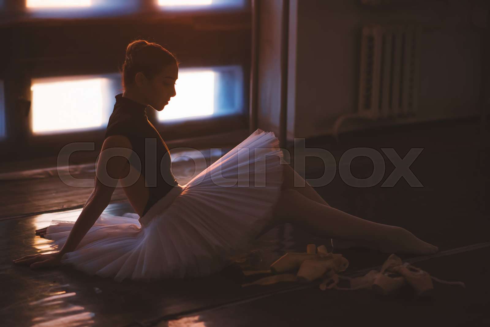 Ballerina sitting on floor in dark ballet class | Stock image | Colourbox