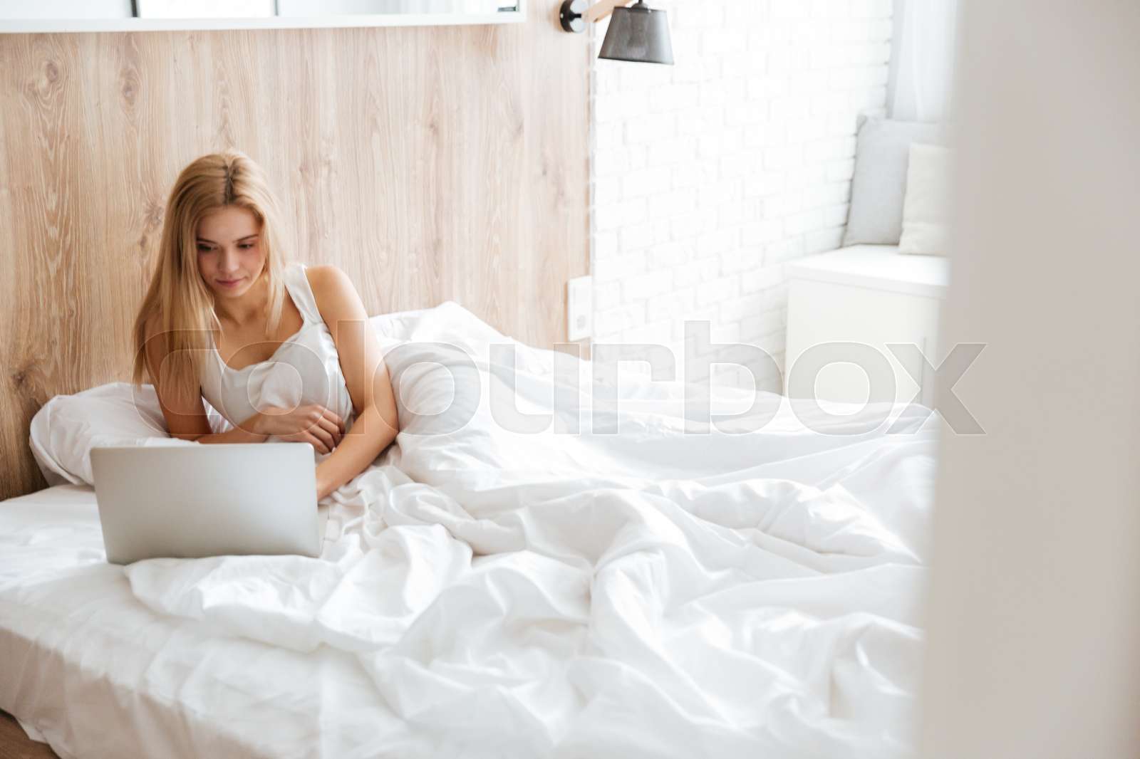 Woman lying on bed with laptop | Stock image | Colourbox