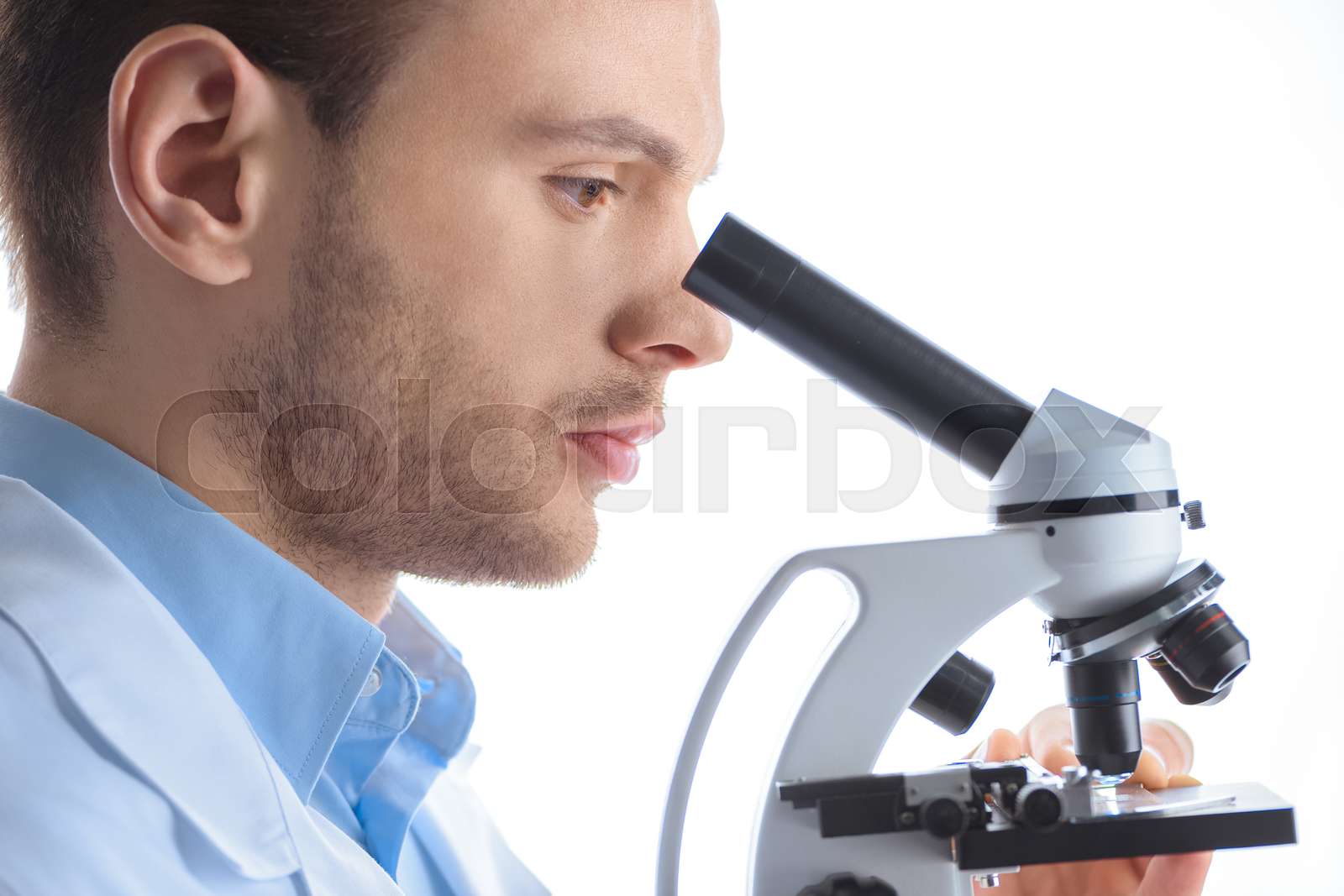 man scientist looking through microscope on white | Stock image | Colourbox