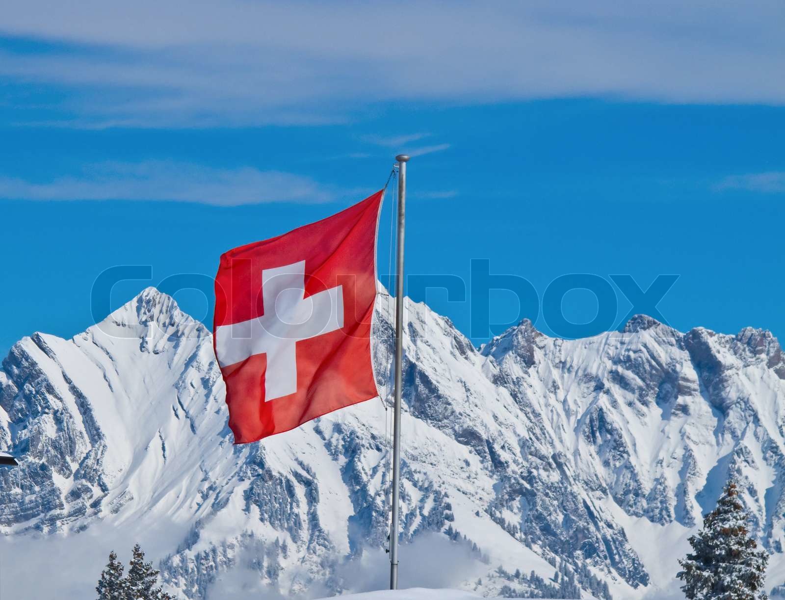 Swiss flag against snowy mountains | Stock image | Colourbox