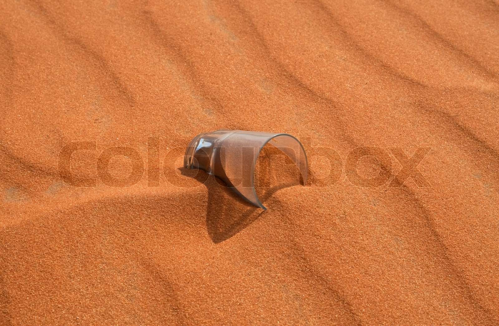Empty glass in the sand | Stock image | Colourbox