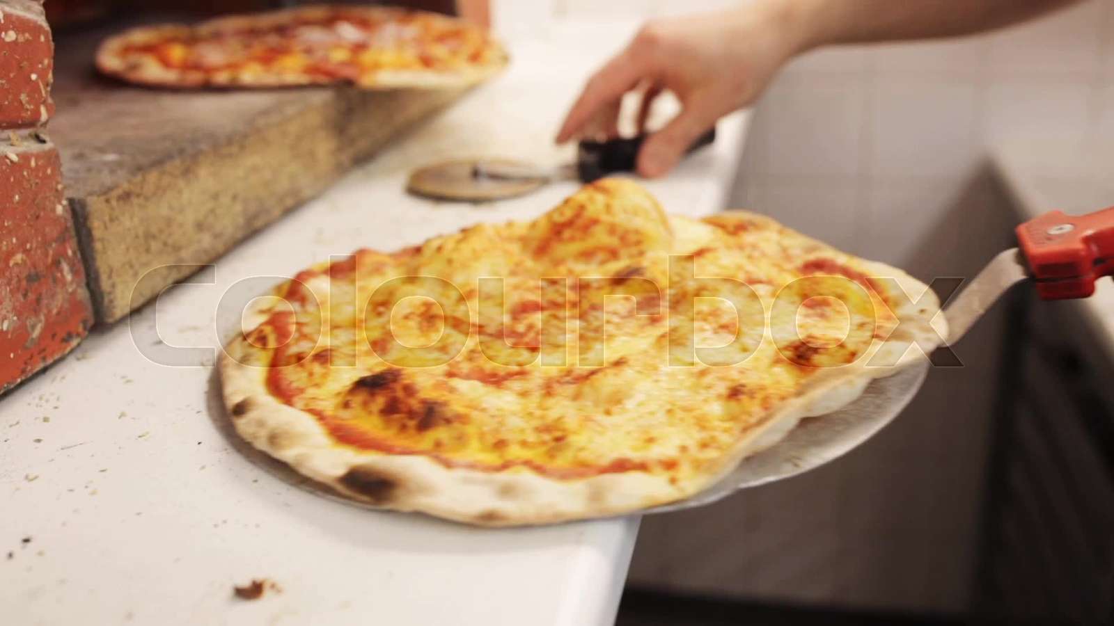cook cutting pizza to pieces at pizzeria | Stock video | Colourbox