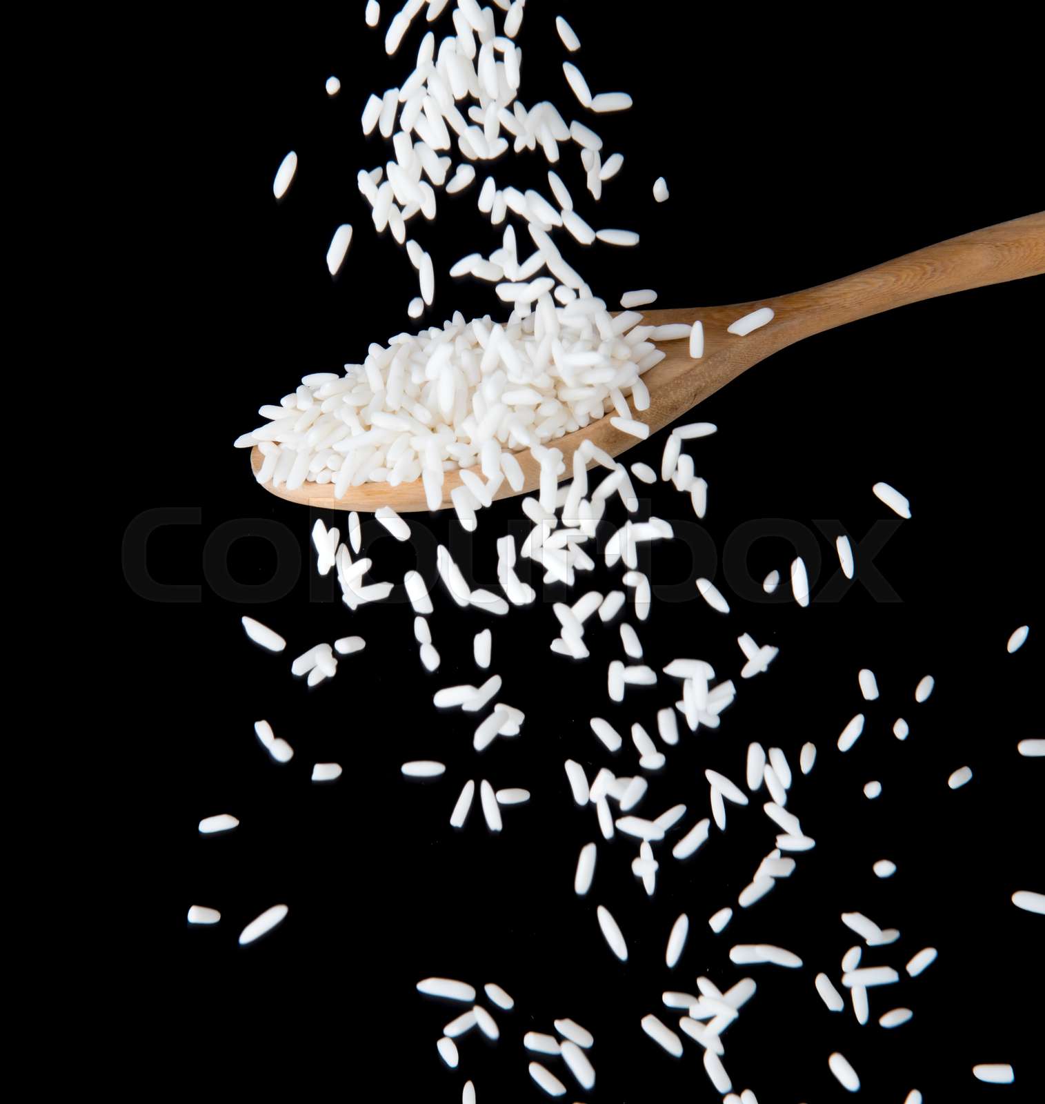 dropped rice grain down from a spoon isolated on black background ...
