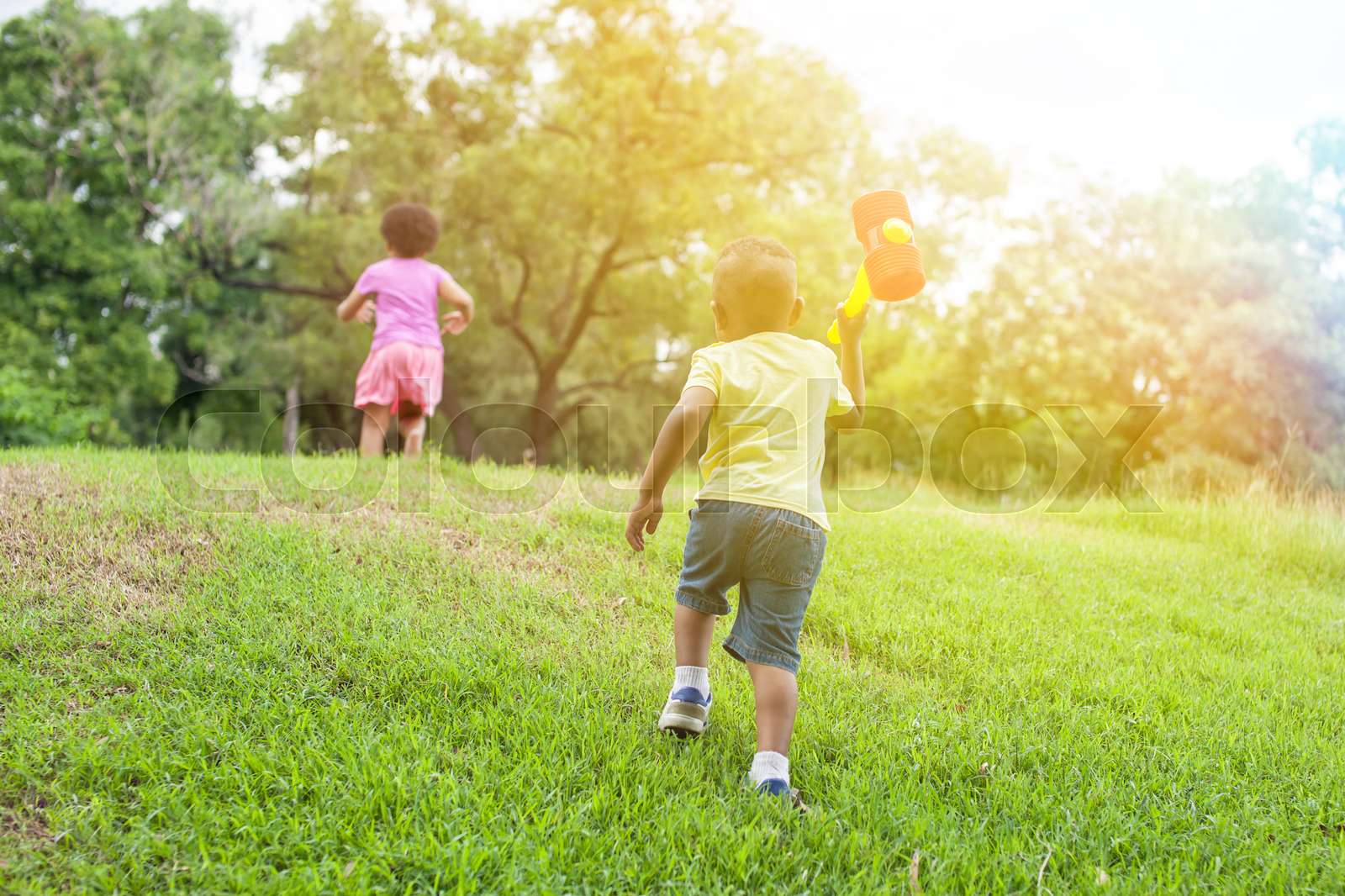 Kids running and chasing after each other in the green park in summer ...