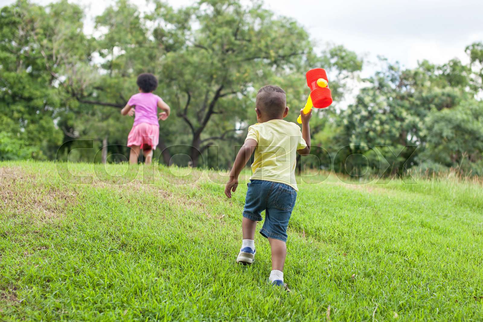 Kids running and chasing after each other in the green park in summer ...