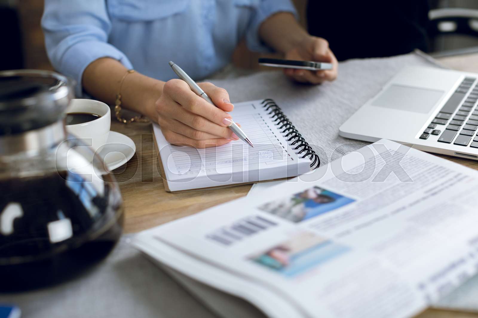 woman taking notes while using smartphone | Stock image | Colourbox