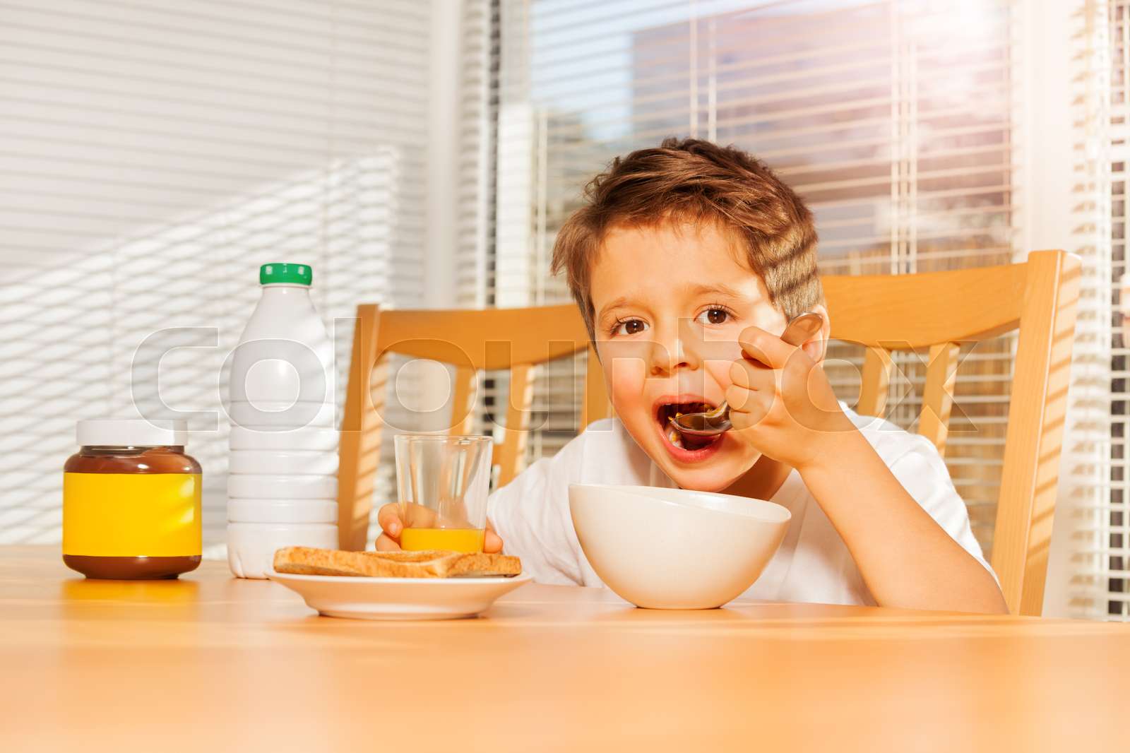 Adorable little boy eating corn flakes in kitchen | Stock image | Colourbox