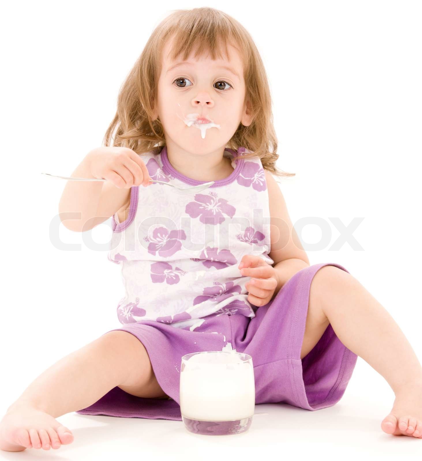 billede af lille pige spiser yoghurt over hvide | Stock foto | Colourbox