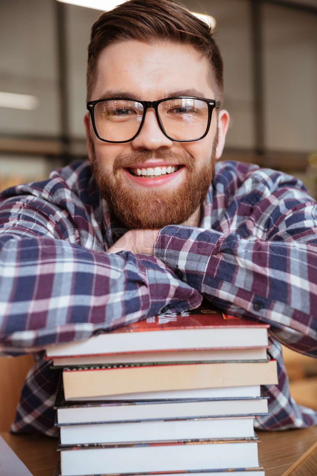 Smiling male student resting on stack of books | Stock image | Colourbox