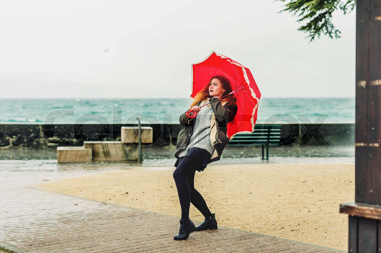 Young girl fighting with wind under the rain on a very stormy day ...