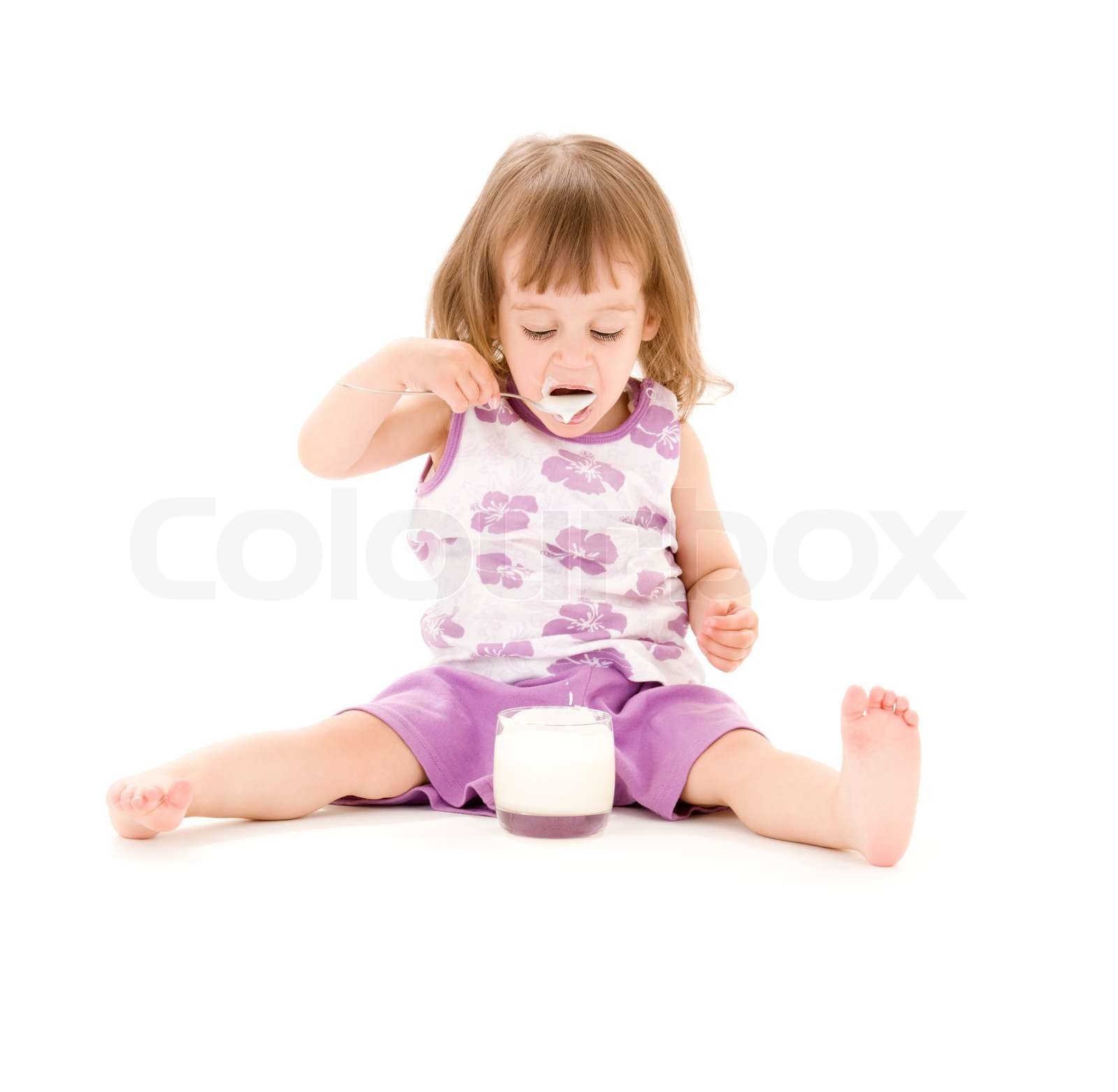 billede af lille pige spiser yoghurt over hvide | Stock foto | Colourbox
