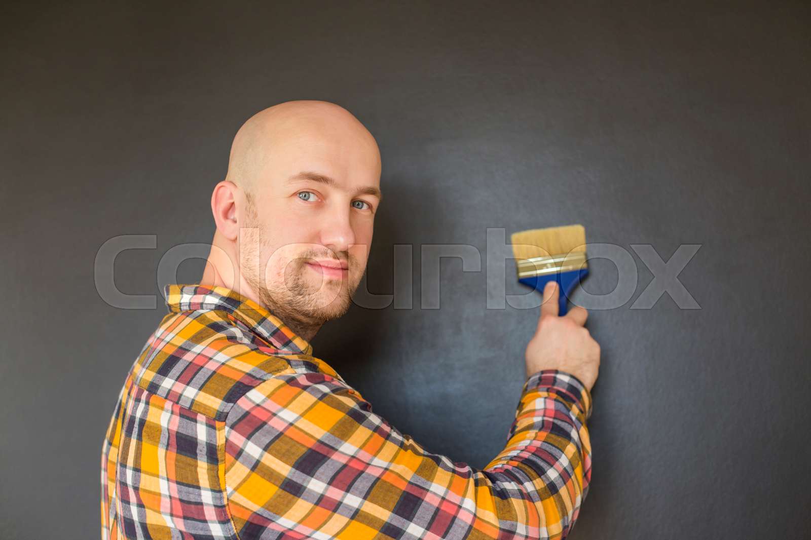 Young man painting wall with black paint. | Stock image | Colourbox