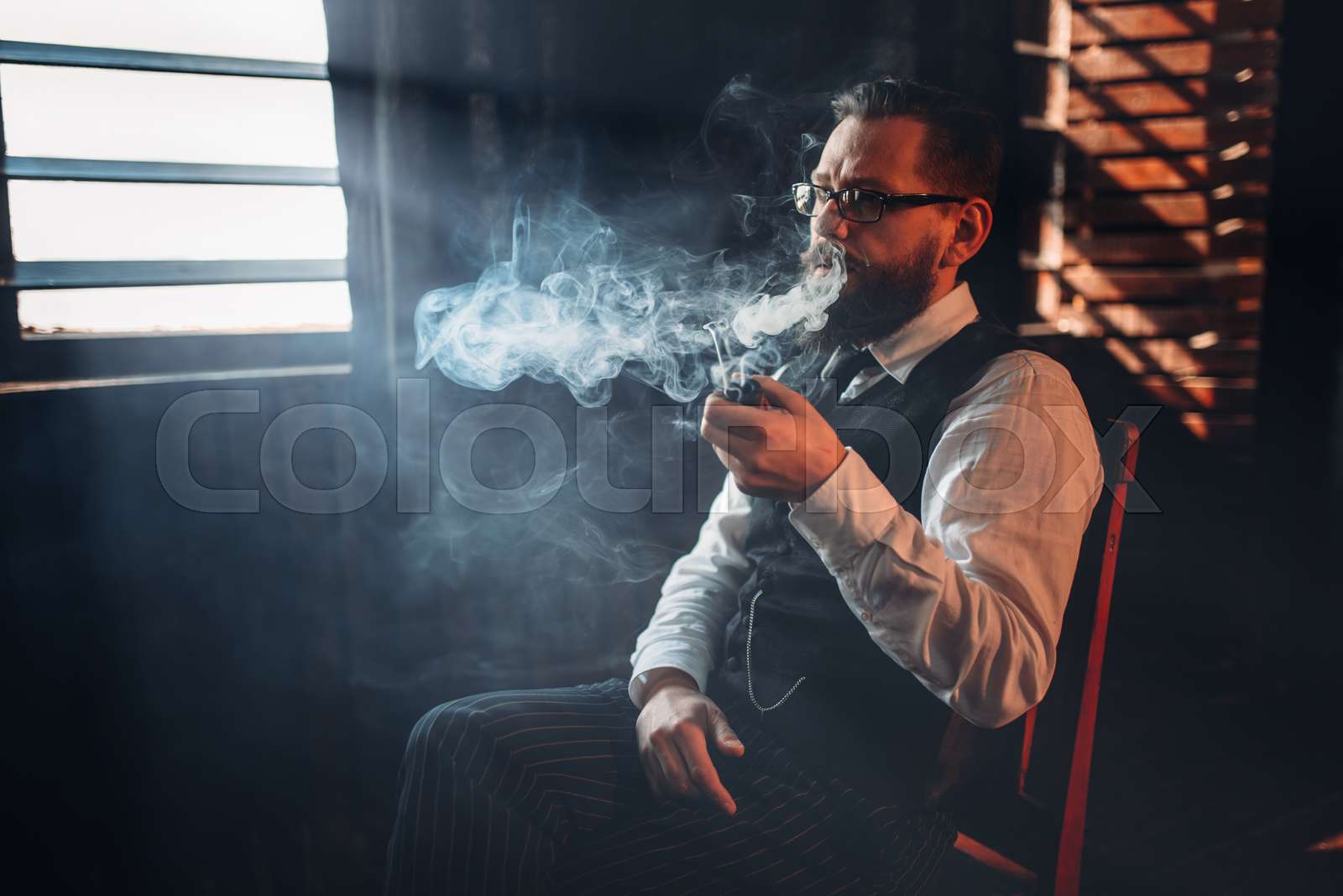 Portrait of man sitting on chair and smoking pipe | Stock image | Colourbox