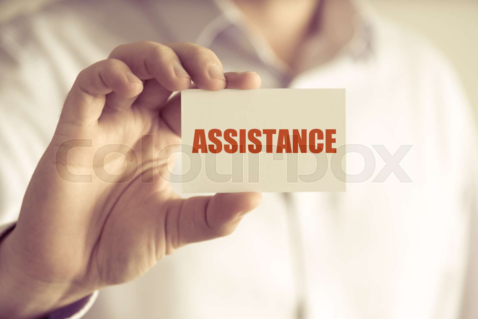 Businessman holding ASSISTANCE message card | Stock image | Colourbox