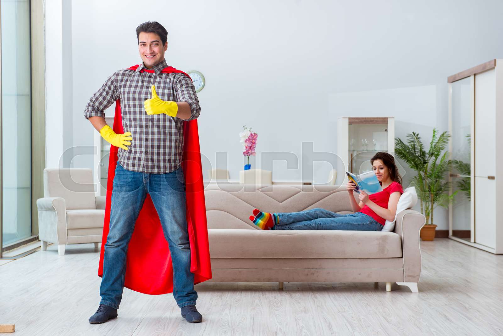 Superhero husband helping his wife at home | Stock image | Colourbox
