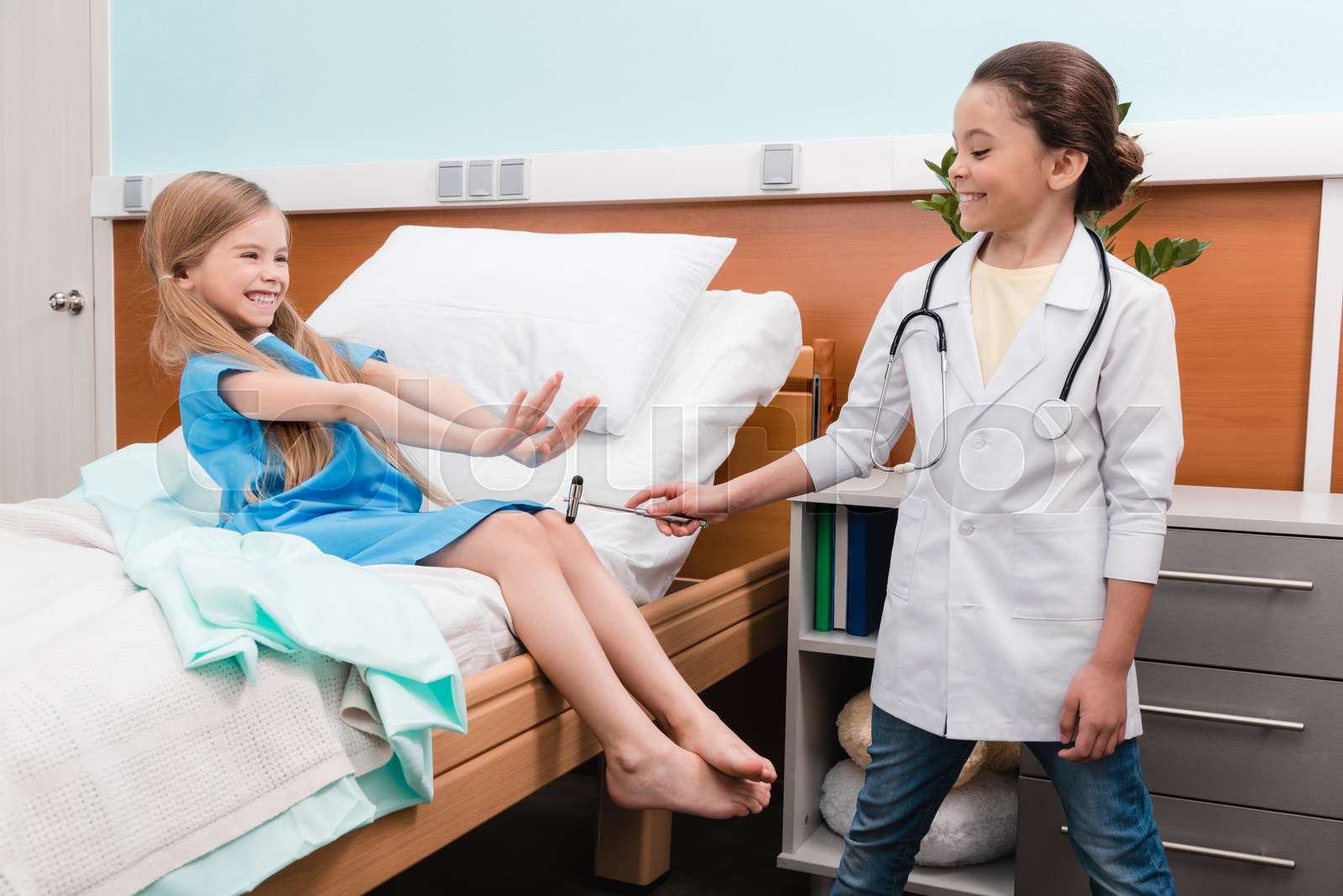 Happy kids playing doctor and patient with reflex hammer in hospital ...