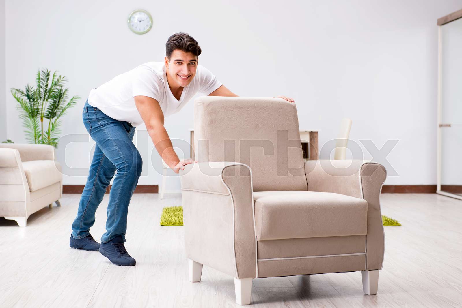Young man moving furniture at home | Stock image | Colourbox