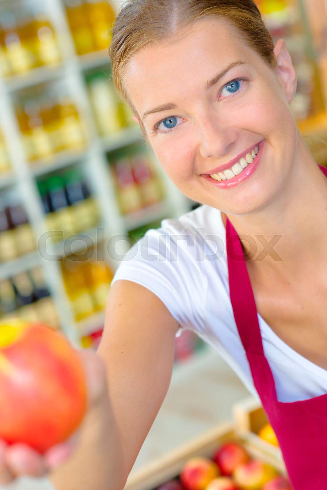 Shop assistant holding up an apple | Stock image | Colourbox
