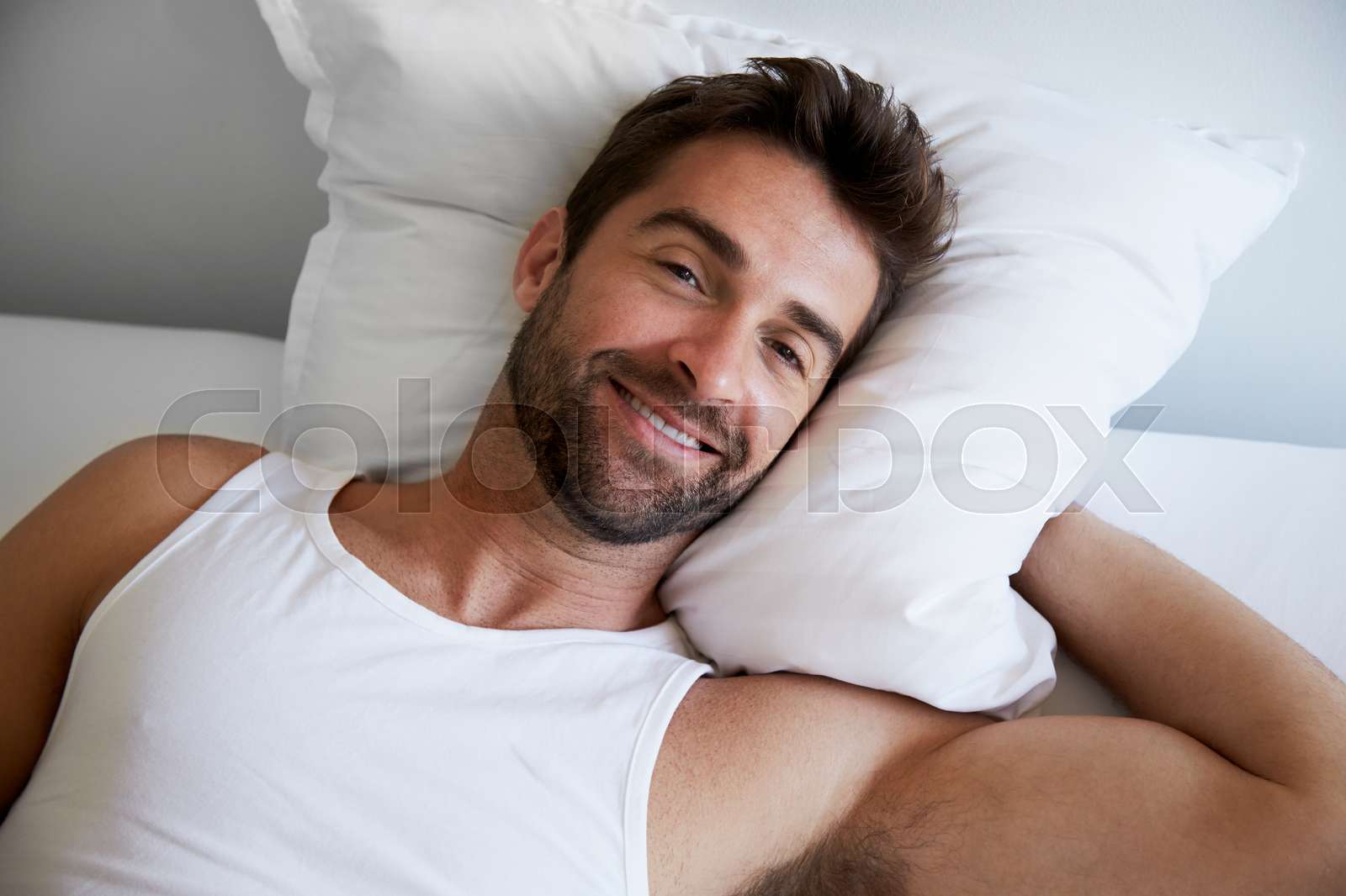 Smiling man in bed | Stock image | Colourbox
