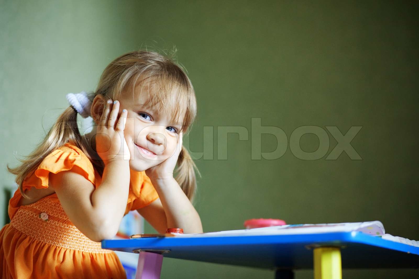 Schönes Kind sitzt am Tisch Blick in die Kamera und lächelt | Stock ...