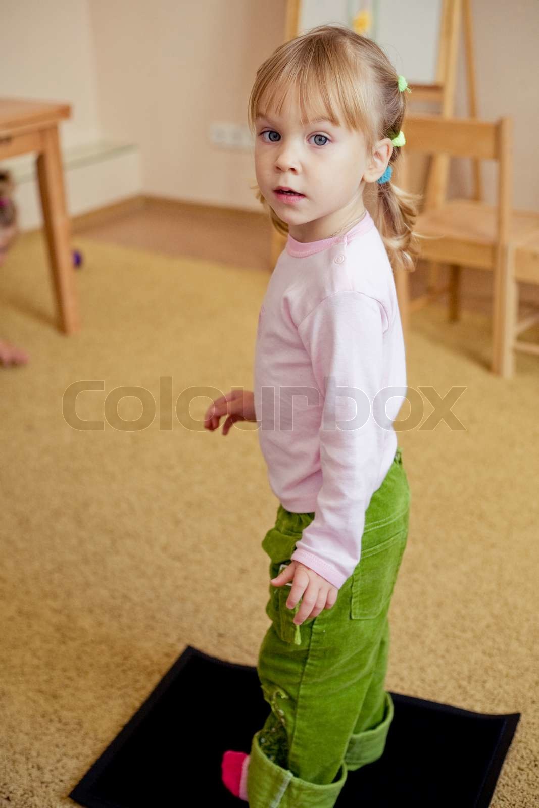 Child in classroom staying on mat | Stock image | Colourbox