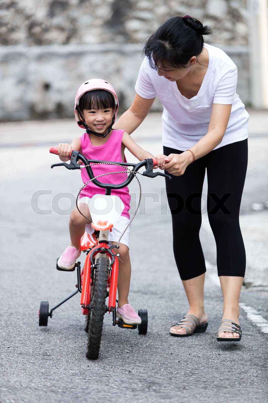 Asian Chinese little girl riding bicycle with mom guide | Stock image ...