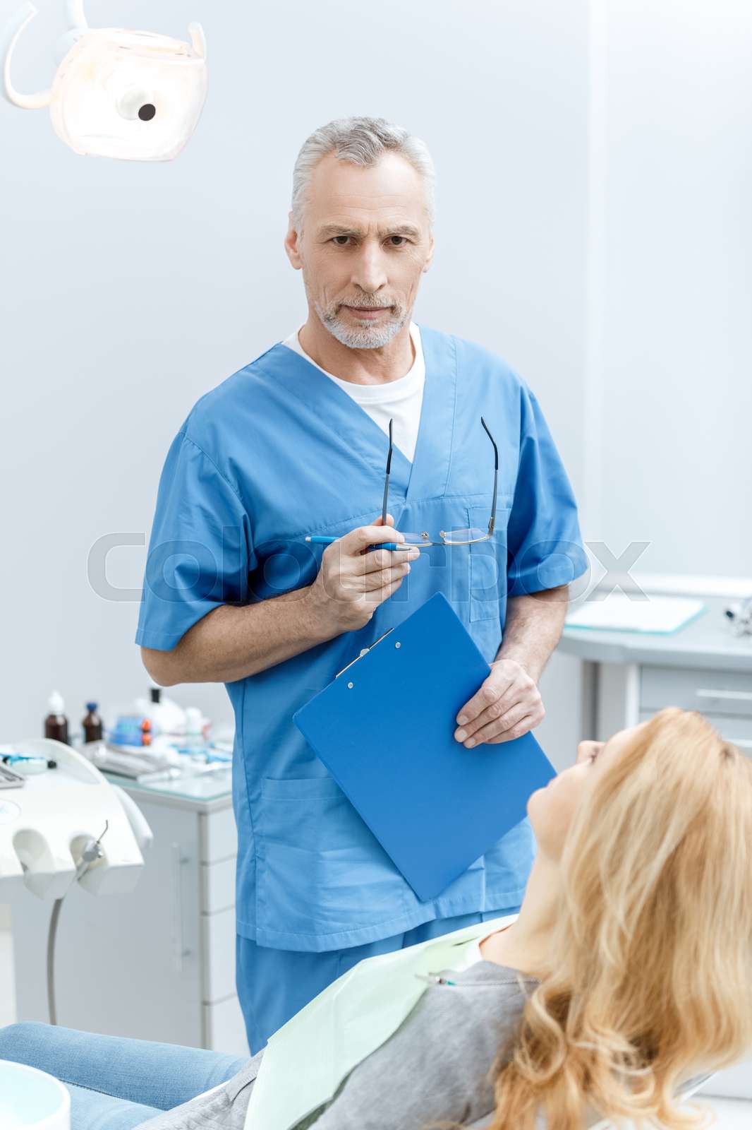 senior dentist in uniform talking with patient in dental clinic | Stock ...