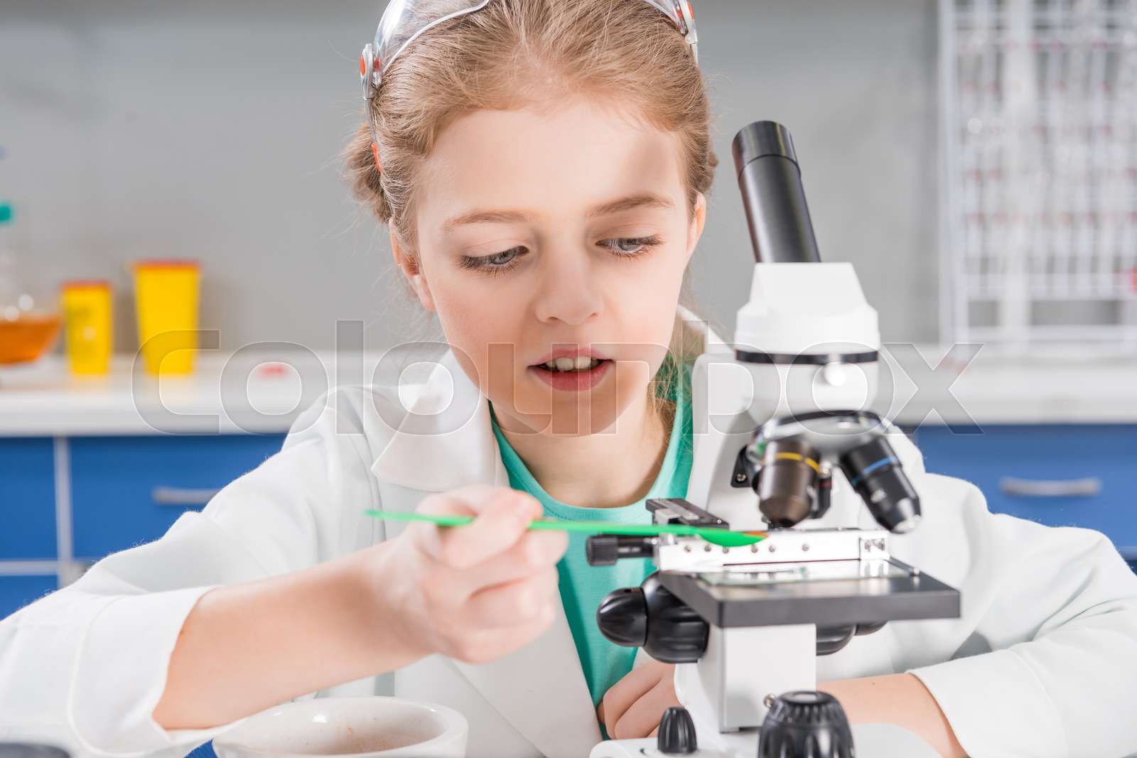 concentrated adorable little girl in goggles with microscope in laboratory | Stock image | Colourbox
