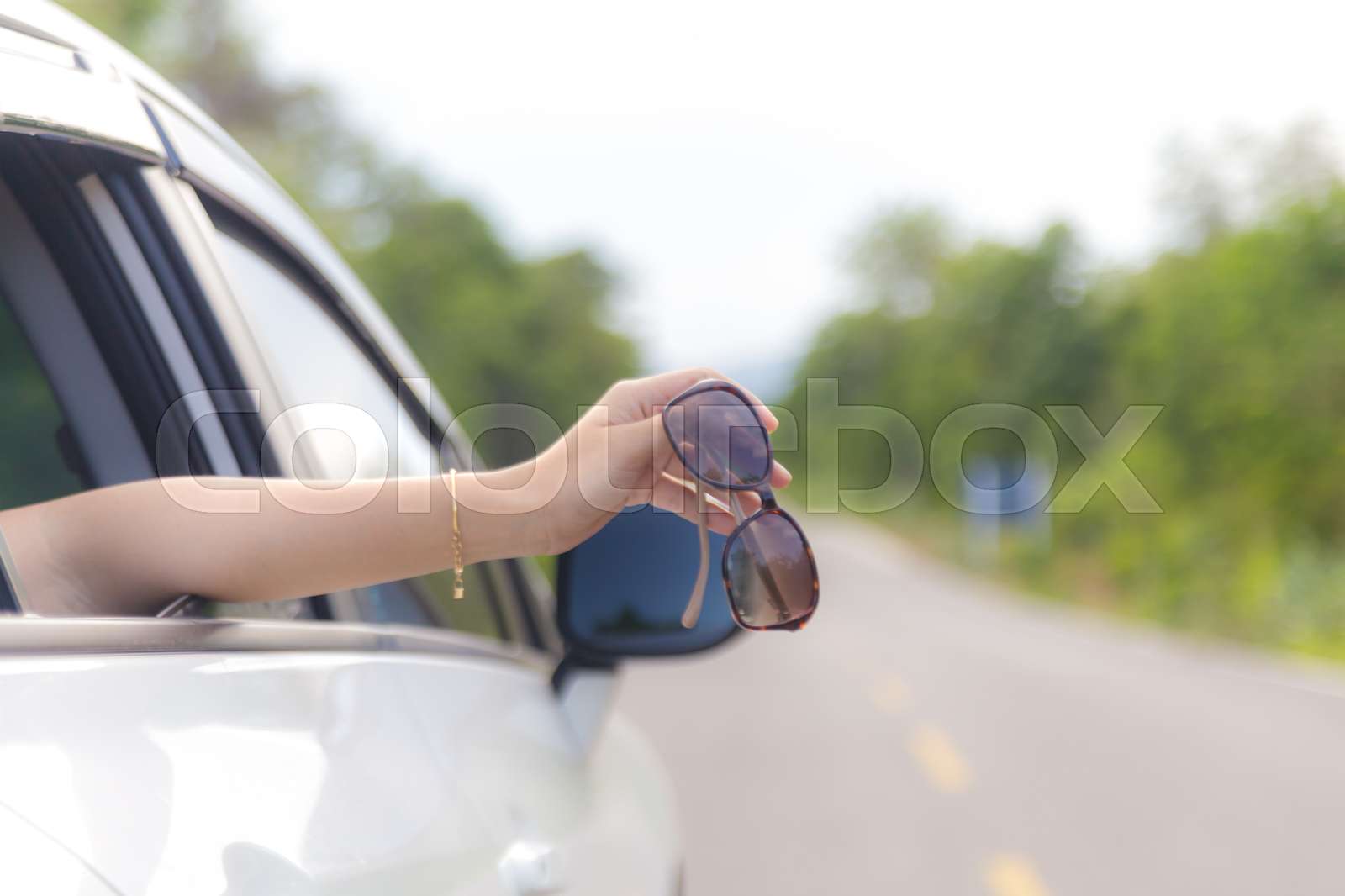 Woman hand at the car window on an country road | Stock image | Colourbox