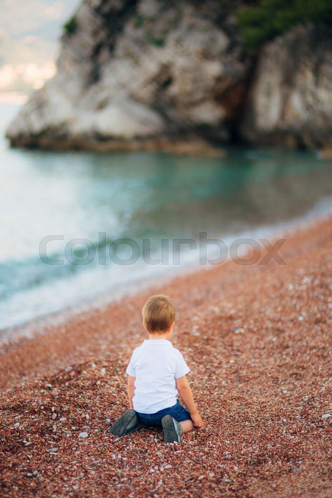 A frustrated child cries on a pebble beach | Stock image | Colourbox