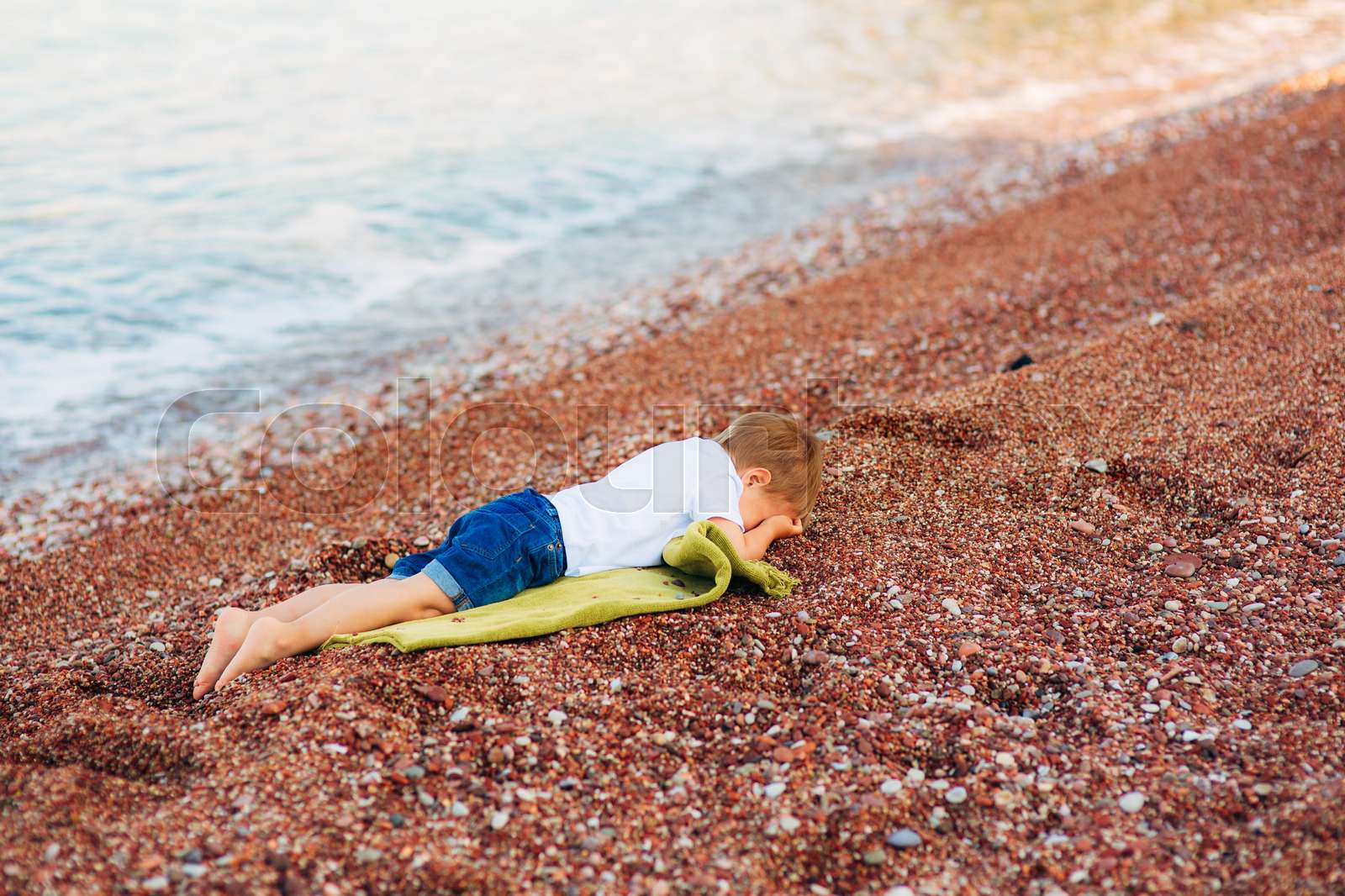 A frustrated child cries on a pebble beach | Stock image | Colourbox
