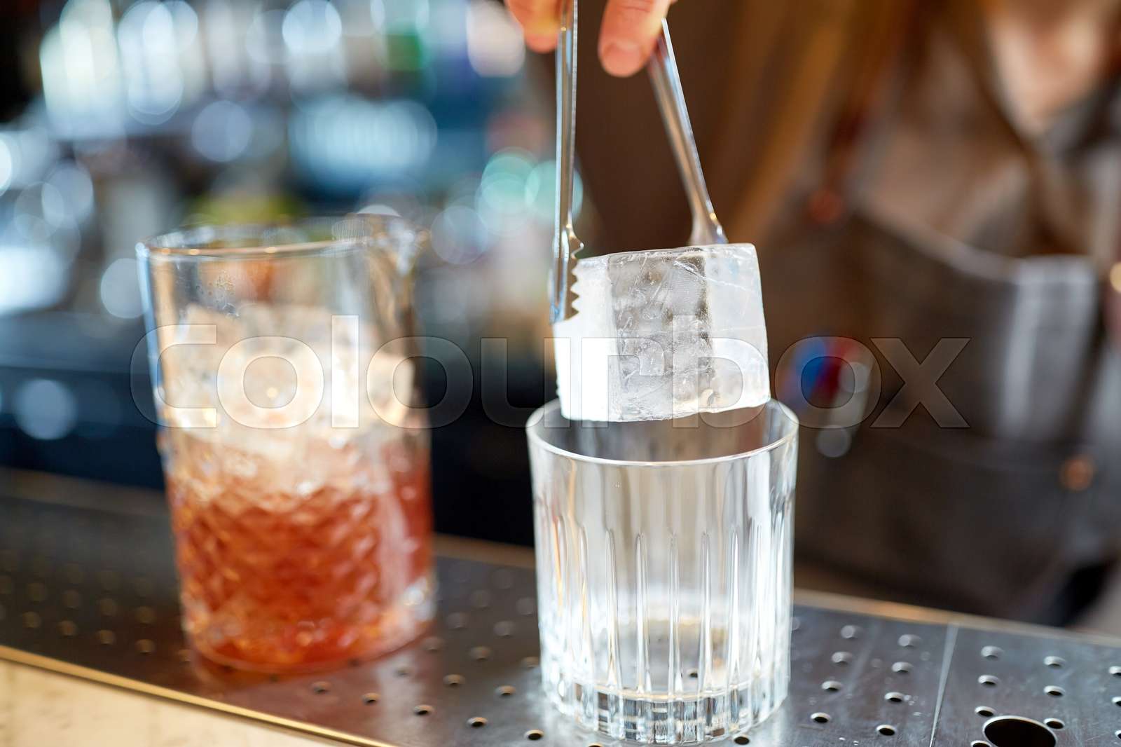 bartender adding ice cube into glass at bar | Stock image | Colourbox