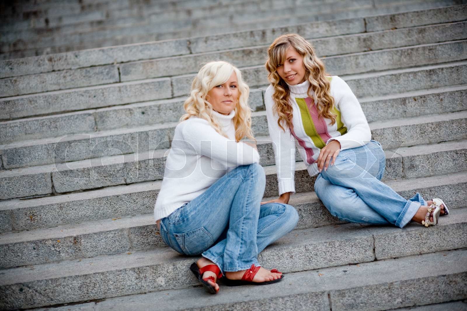 Two beautiful girls friends sitting on staircase and talking | Stock ...