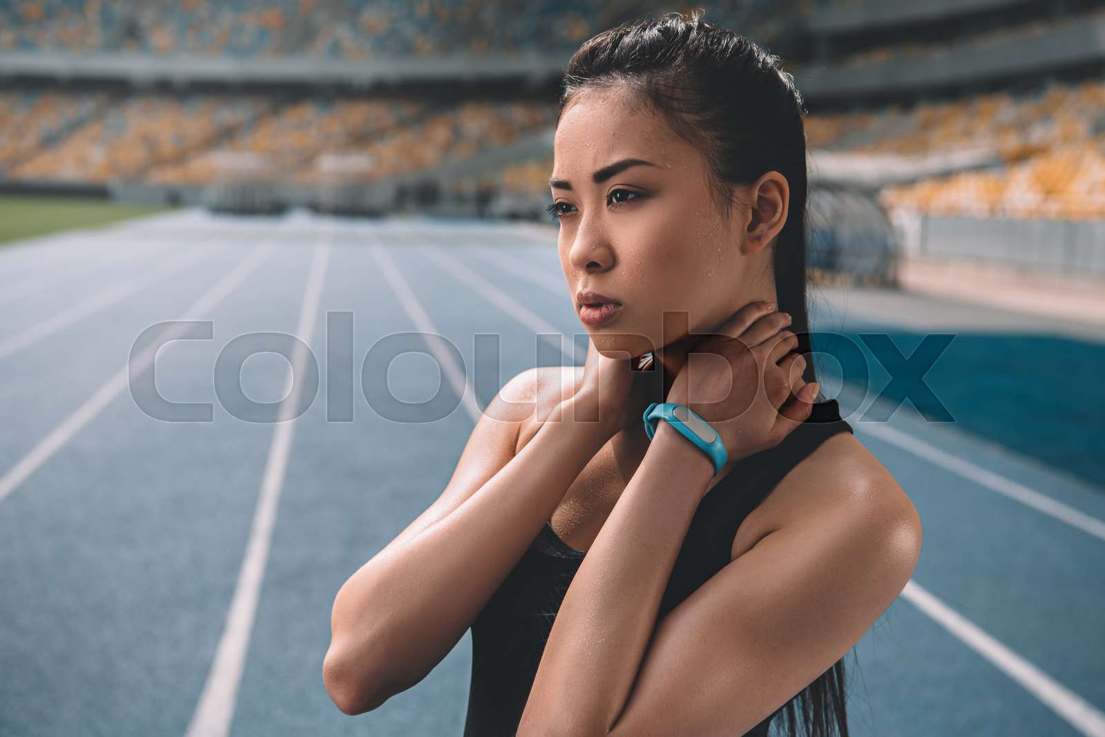Young asian sportswoman standing on running track stadium and looking ...