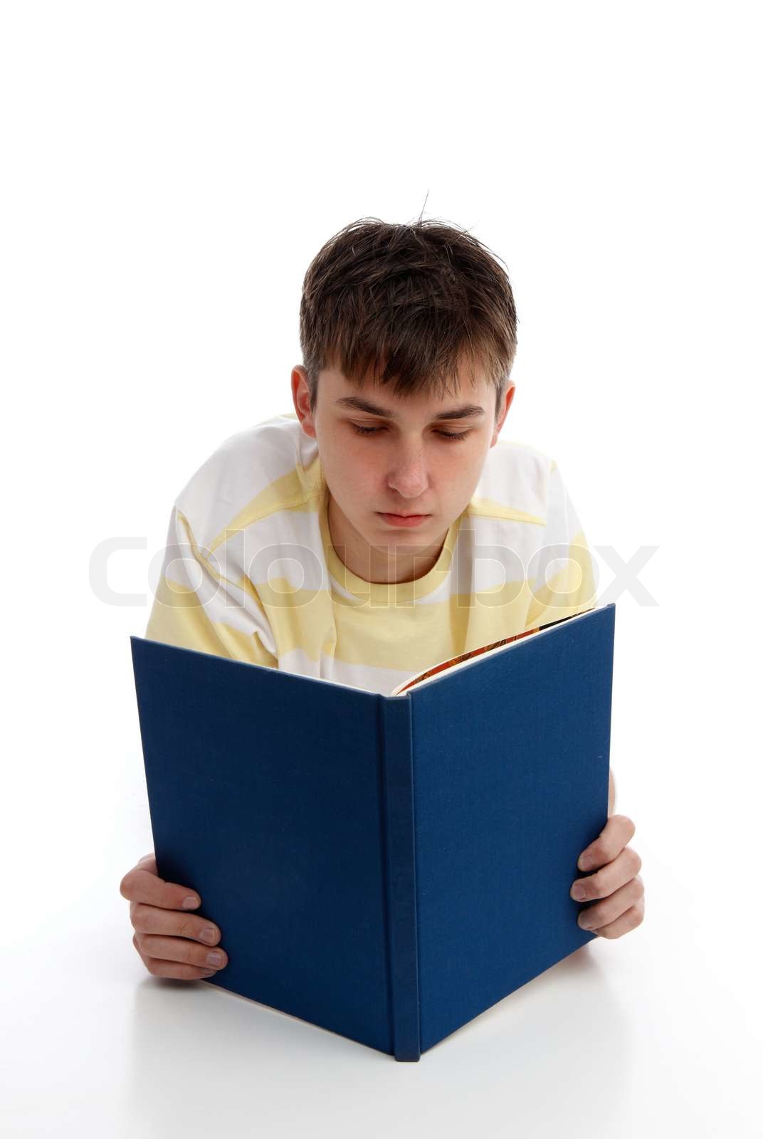 A boy reading a book, textbook, studying, learning or recreational ...