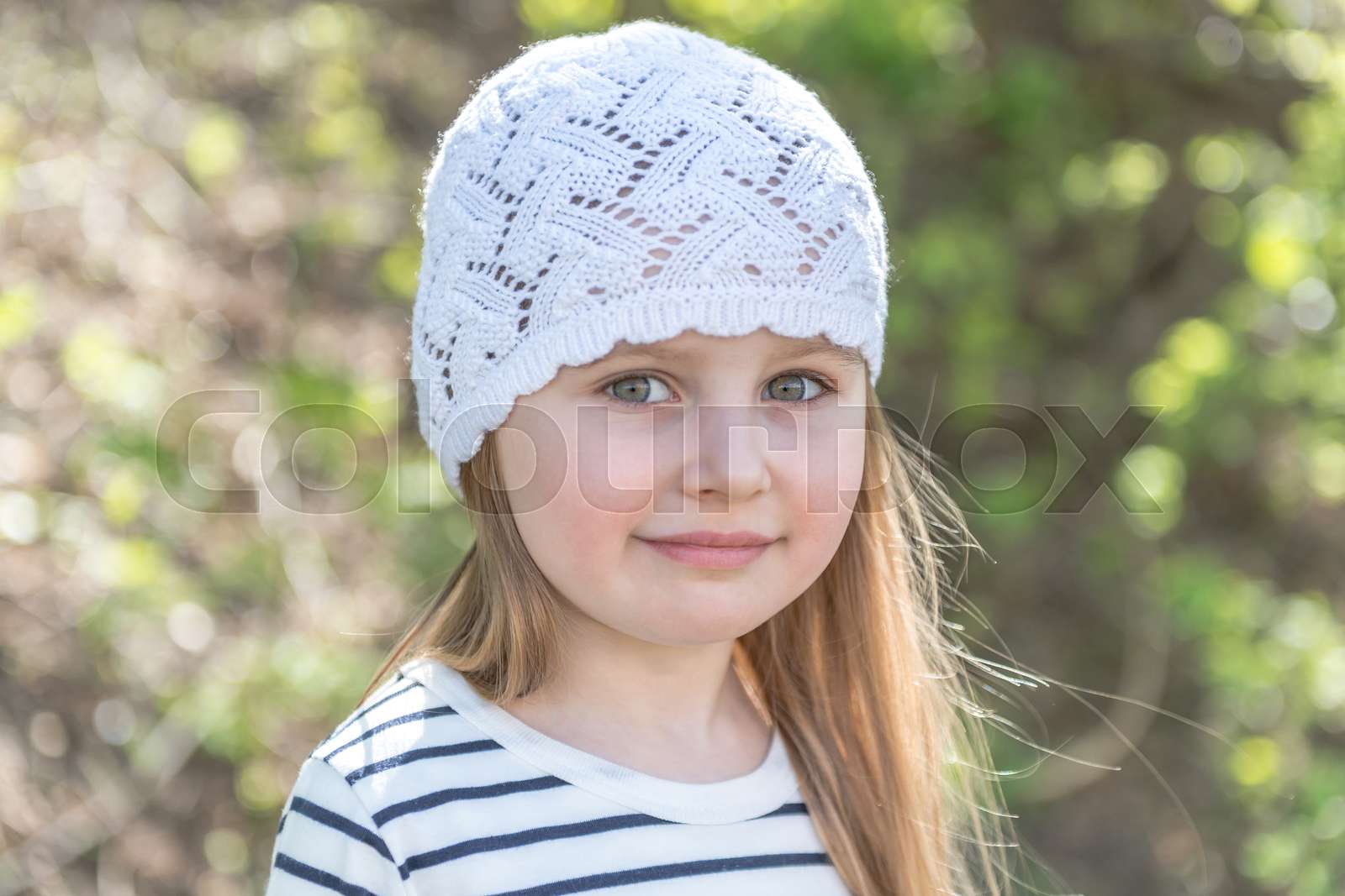 Cute little girl smiling shyly, standing outside | Stock image | Colourbox