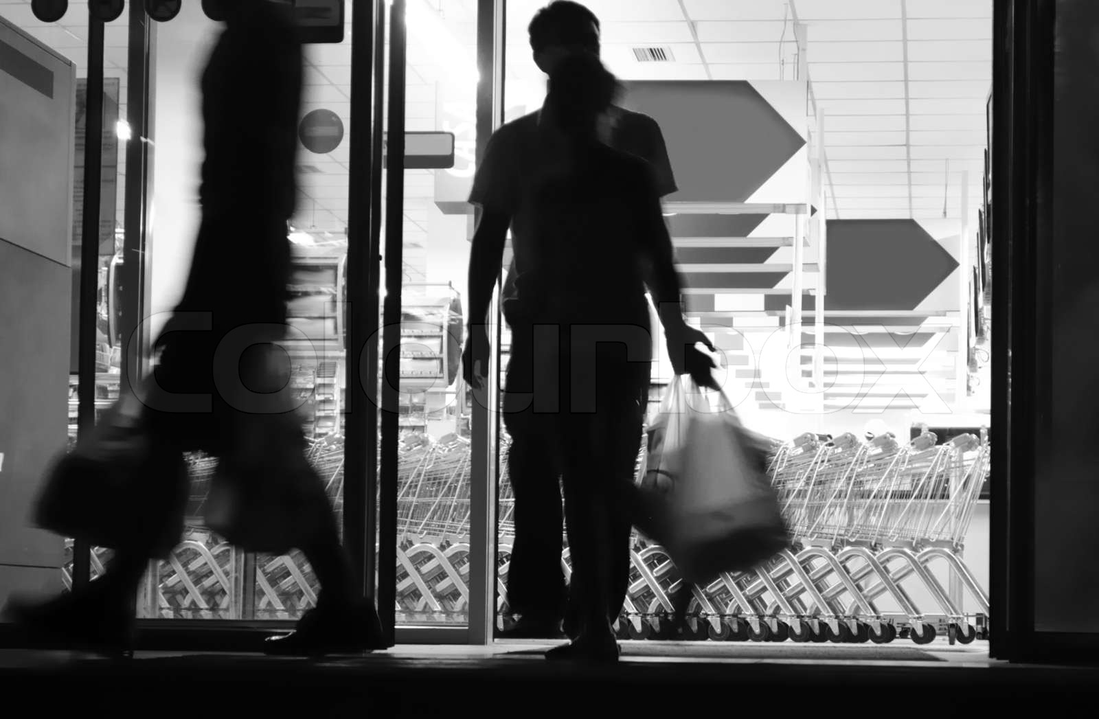 This photograph represent silhouettes of shoppers exiting grocery store ...