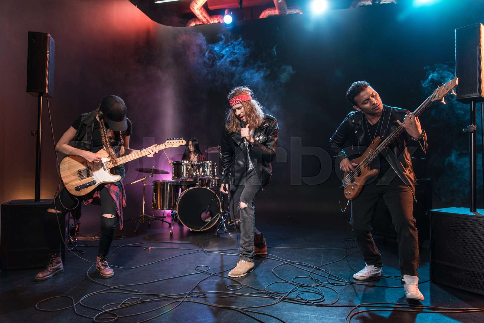 Handsome singer with rock and roll band performing music on stage ...