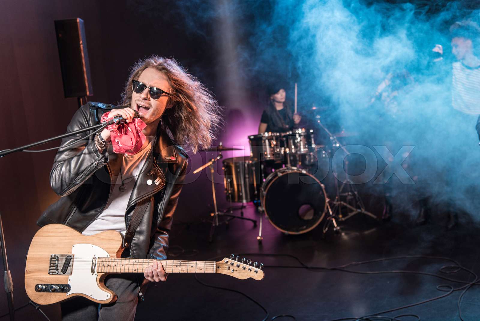 Male singer with microphone and rock and roll band performing hard rock ...