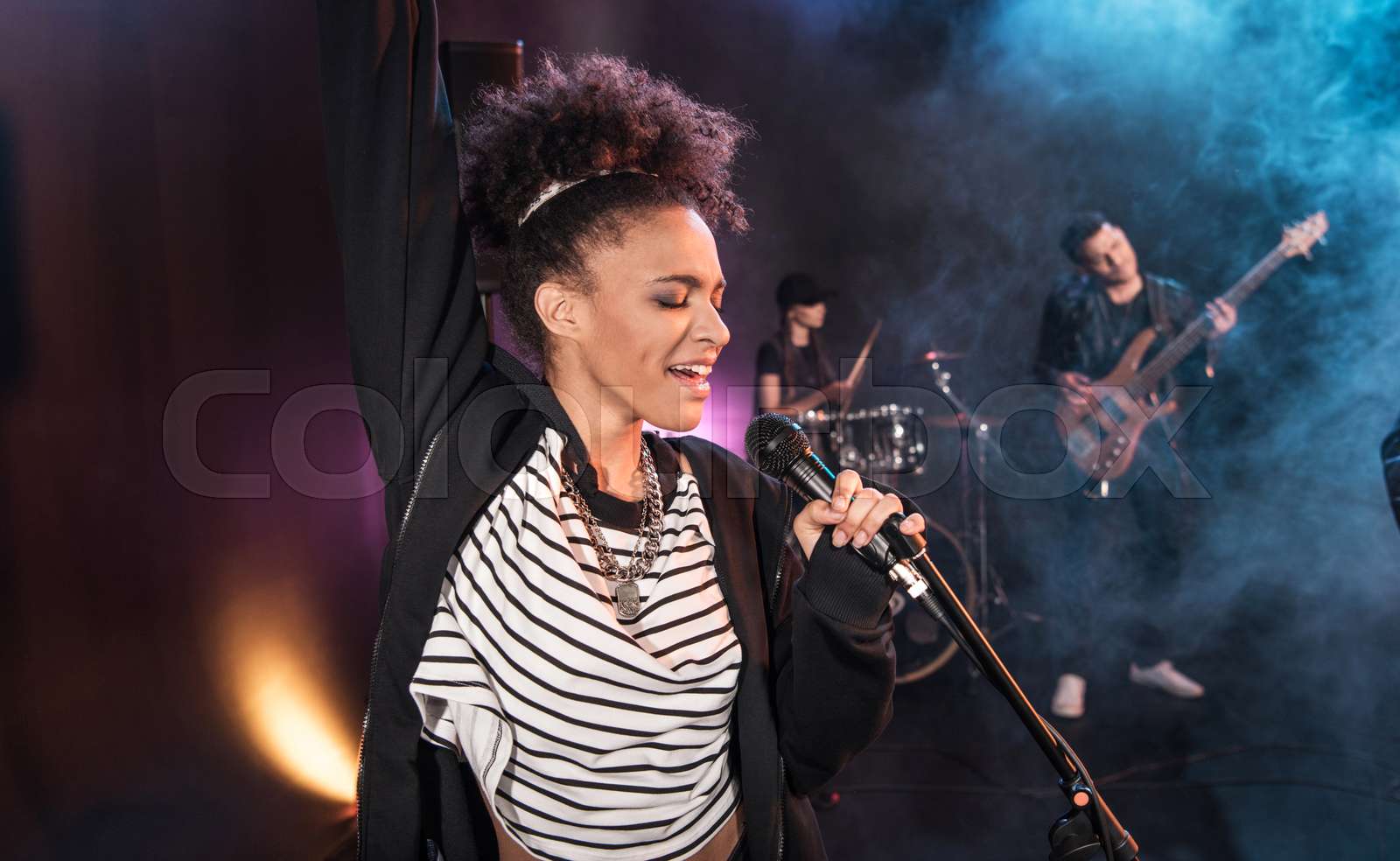 Female singer with microphone and rock and roll band performing hard ...