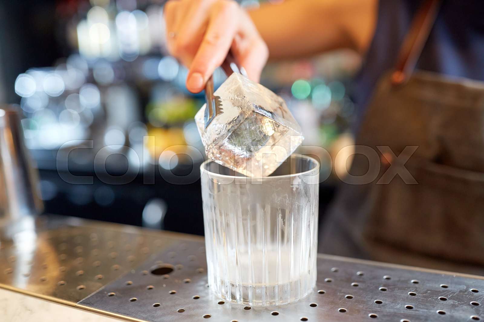 bartender adding ice cube into glass at bar | Stock image | Colourbox