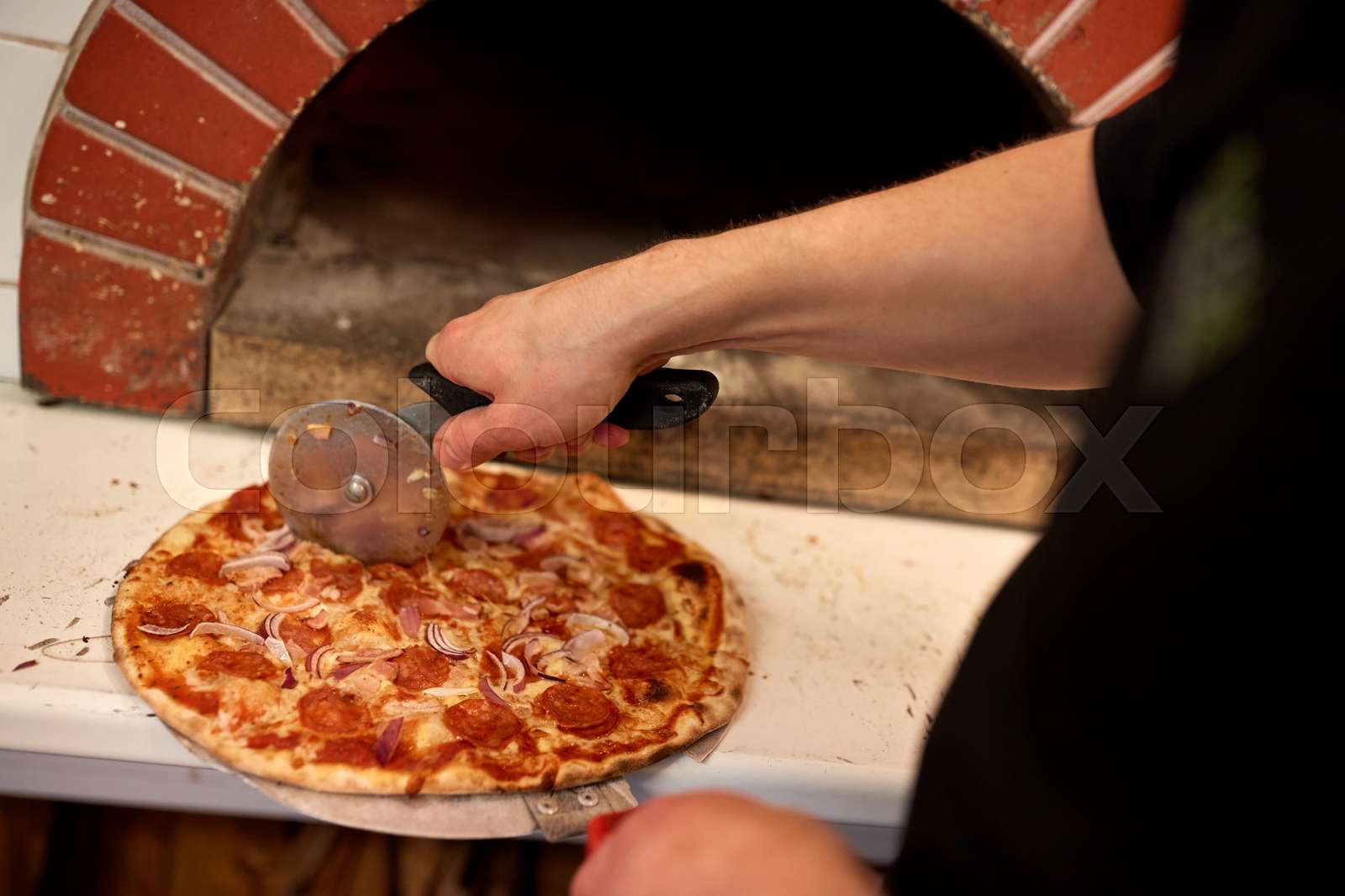 cook hands cutting pizza to pieces at pizzeria | Stock image | Colourbox