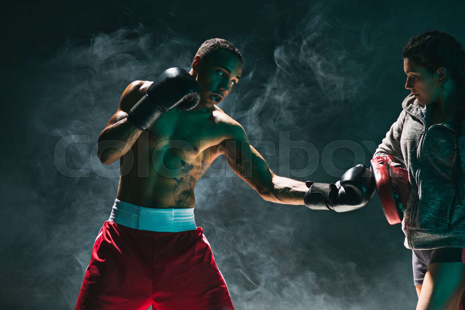 Handsome Afro American boxer with bare torso is practicing punches with ...