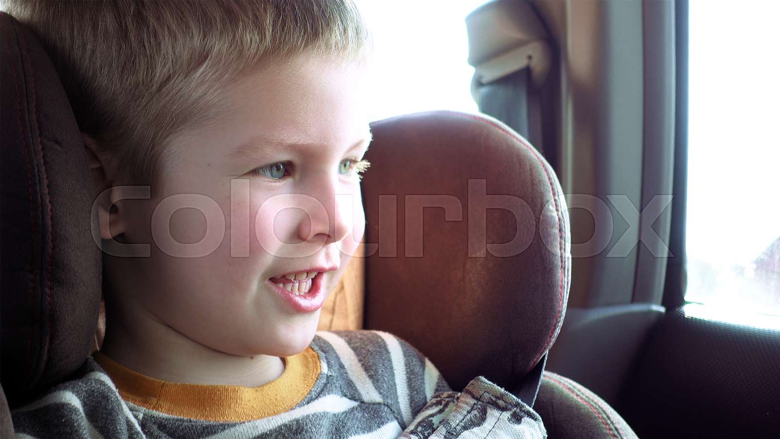 Cute boy in a child car seat smiles and laughs | Stock image | Colourbox
