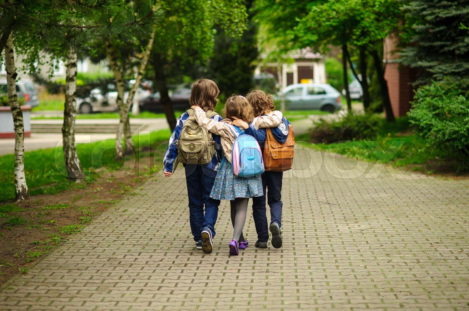 Three little school students, two boys and the girl, go in an embrace ...