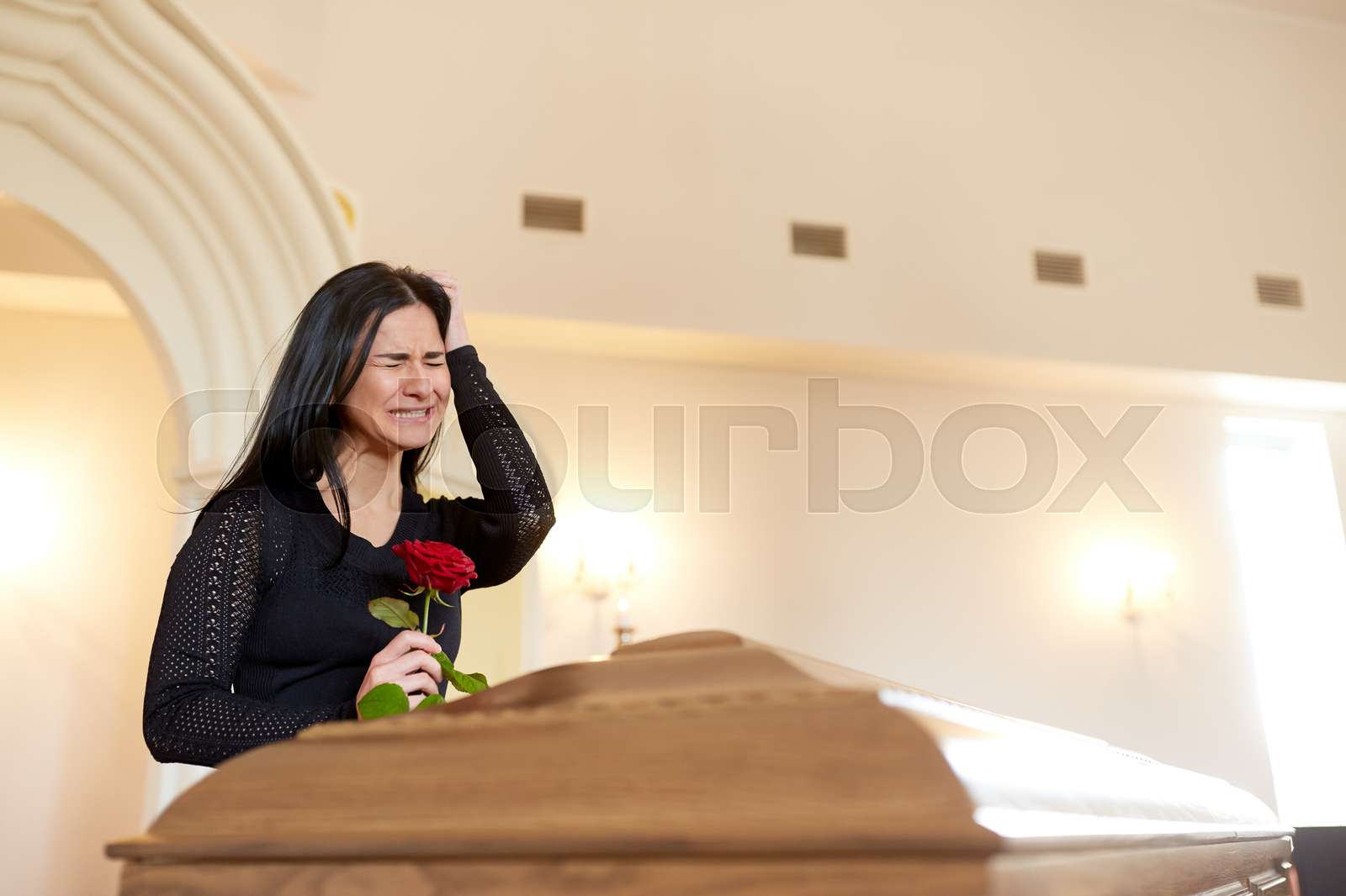 crying woman with red rose and coffin at funeral | Stock image | Colourbox
