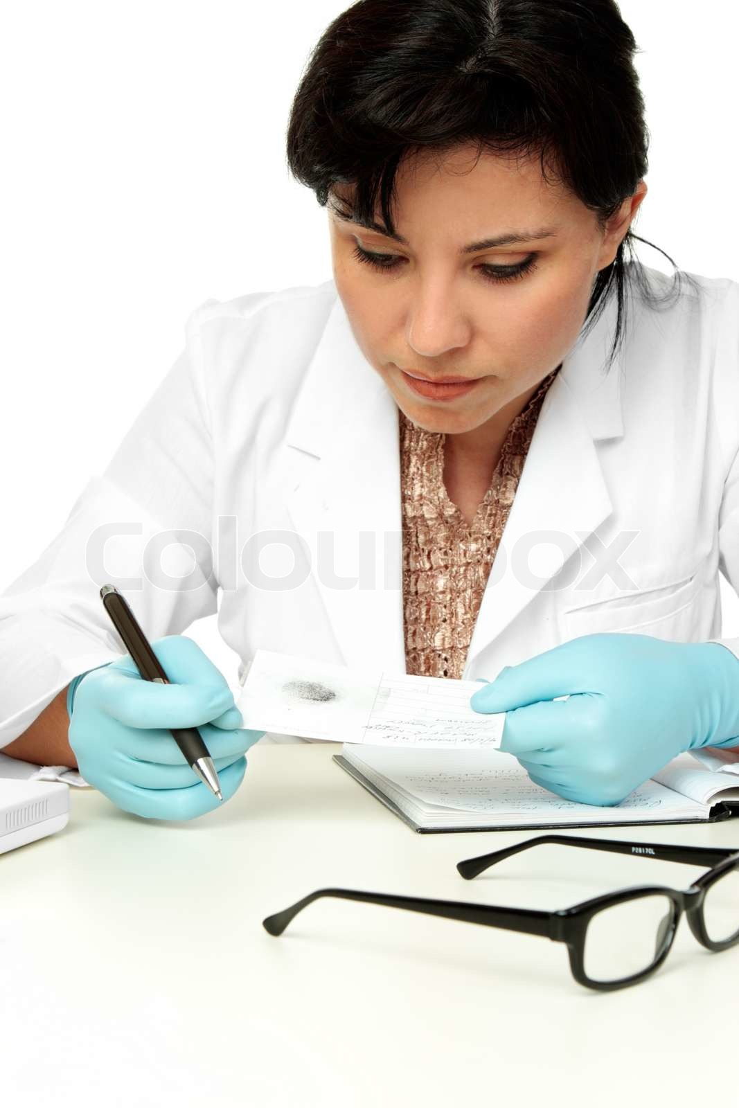 A female forensic scientist holds a fingerprint sample ready for ...